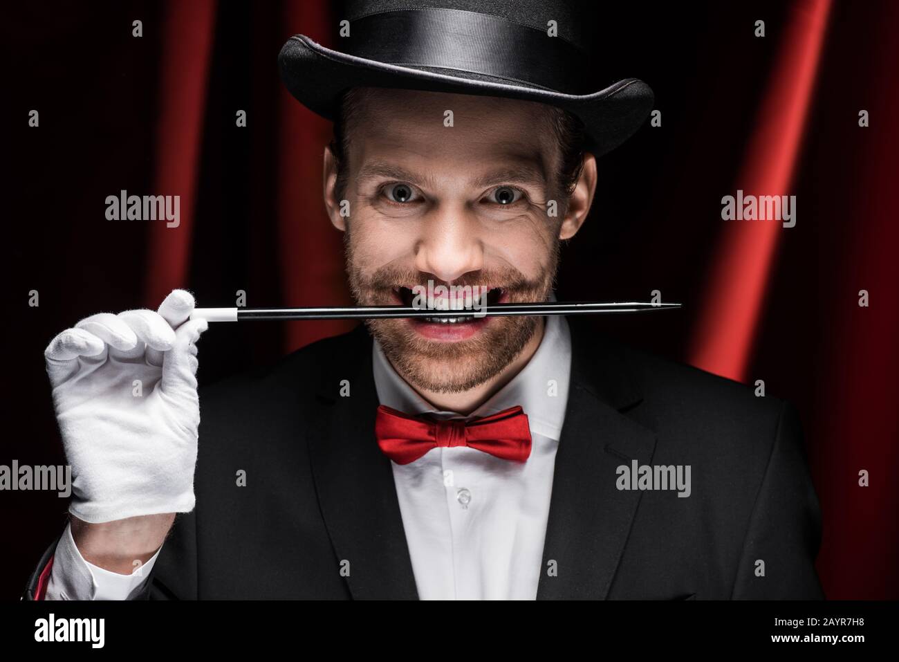 professional scary magician in suit and hat holding wand in teeth in ...