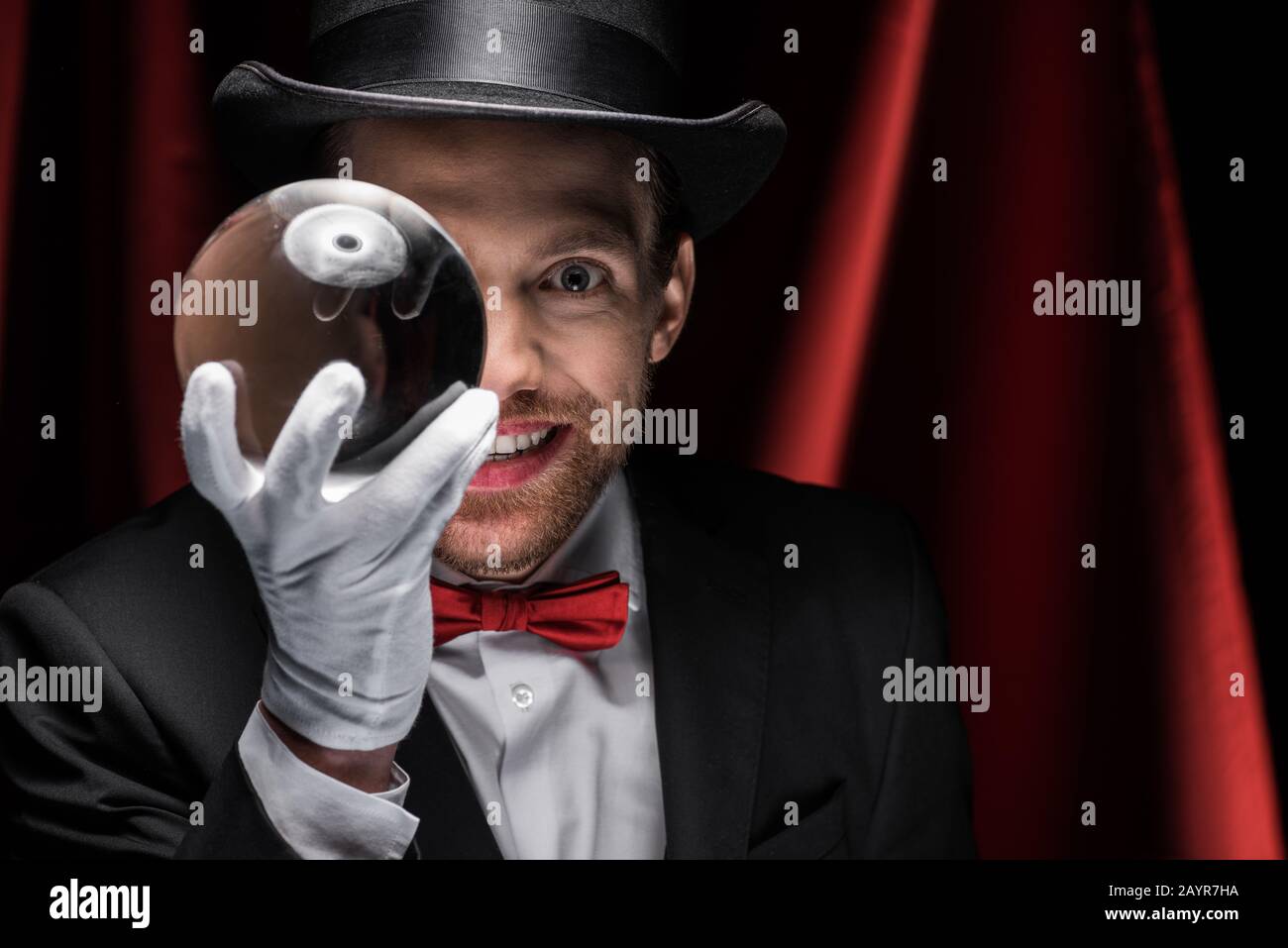 smiling magician holding magic ball in circus with red curtains Stock ...