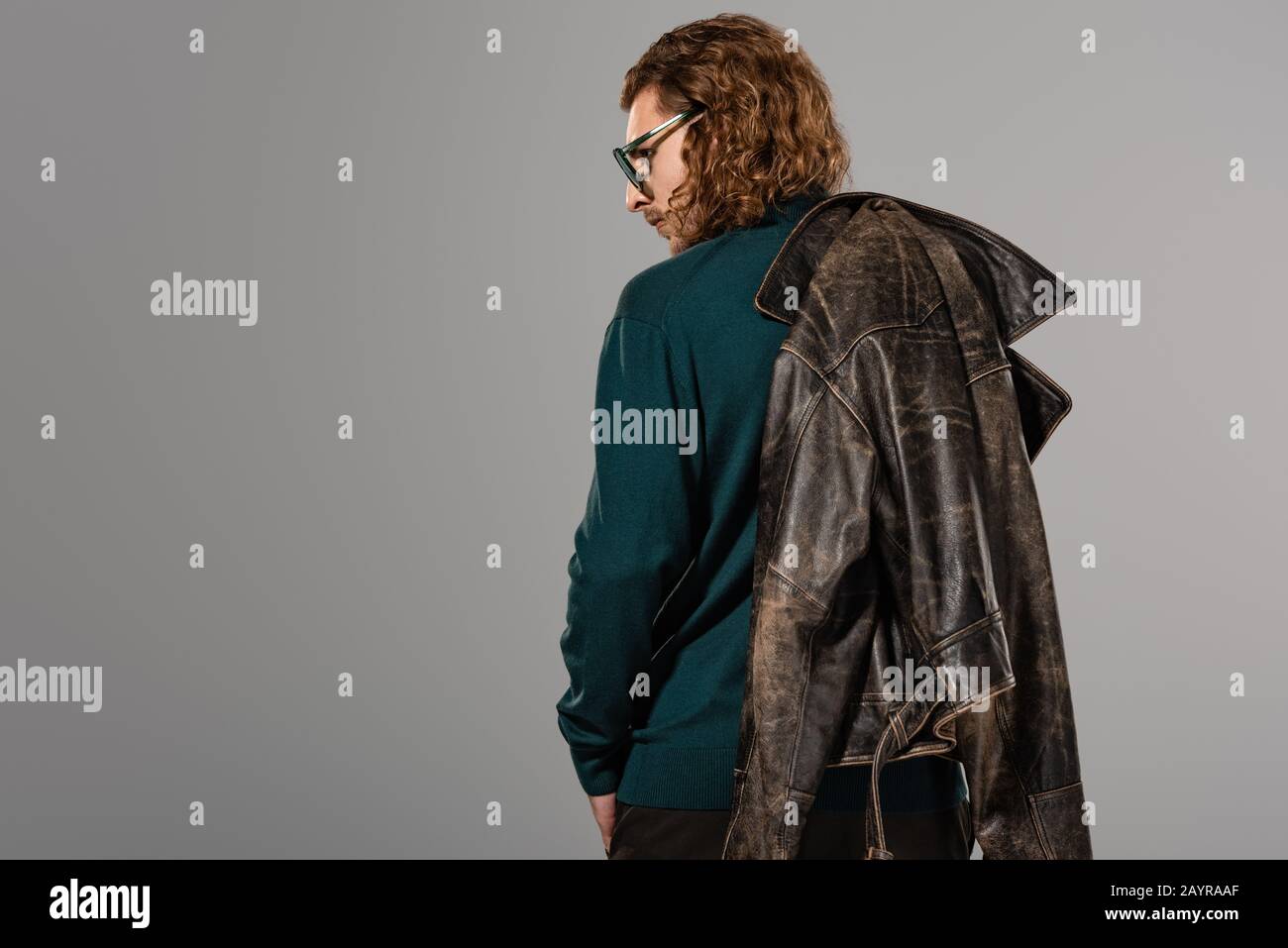 back view of handsome man holding leather jacket isolated on grey Stock ...