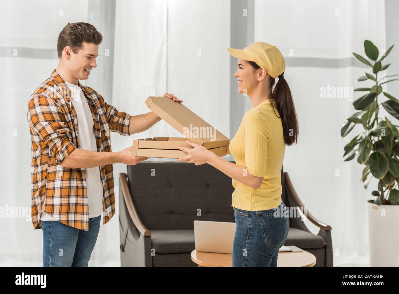 Side view of smiling courier giving pizza boxes to man at home Stock ...