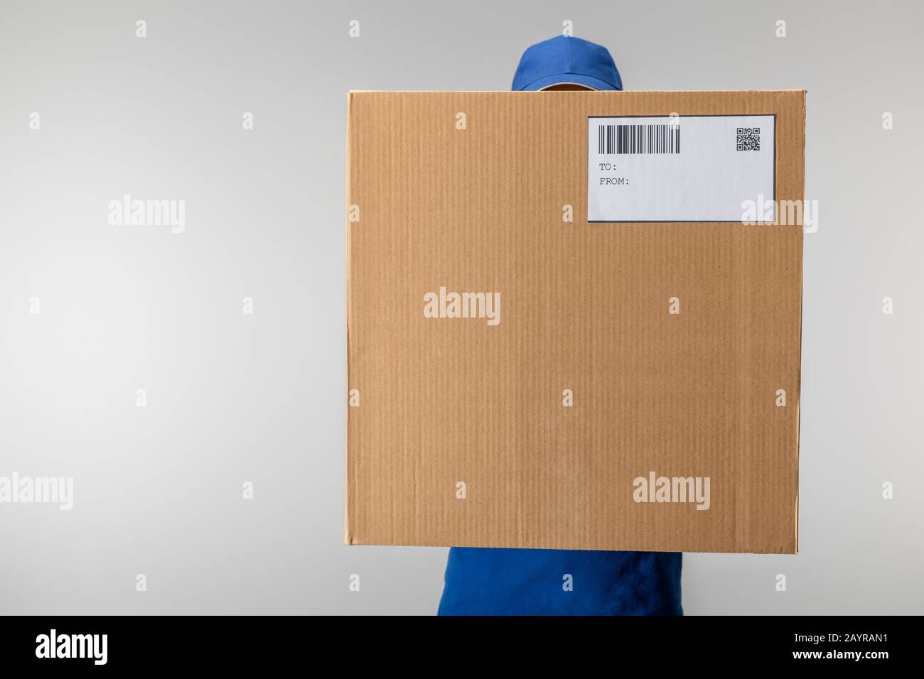 Delivery man in uniform holding cardboard box with qr code and barcode ...
