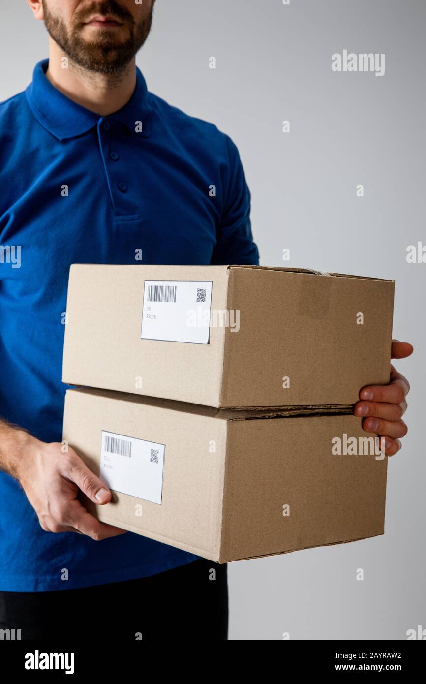 Cropped view of courier holding cardboard boxes with qr codes and ...