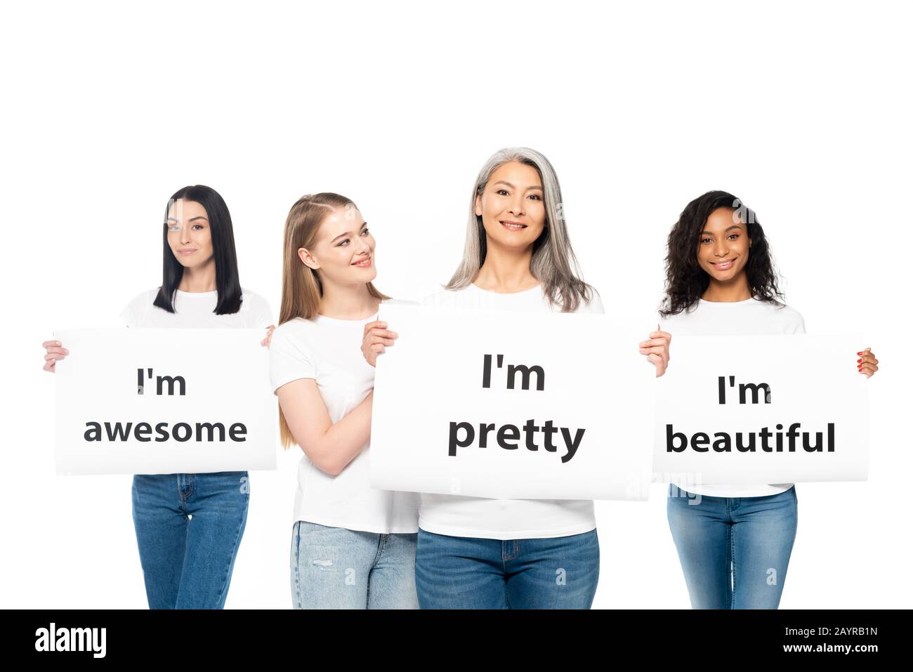 happy multicultural women in jeans holding posters with lettering ...
