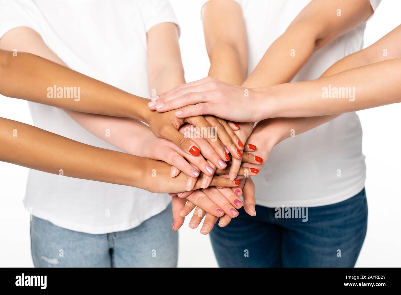 cropped view of four multicultural women putting hands together ...