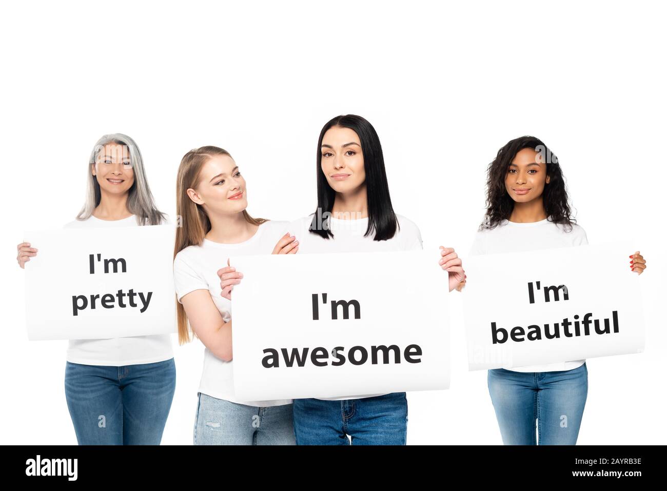 happy multicultural women in denim jeans holding posters with lettering ...