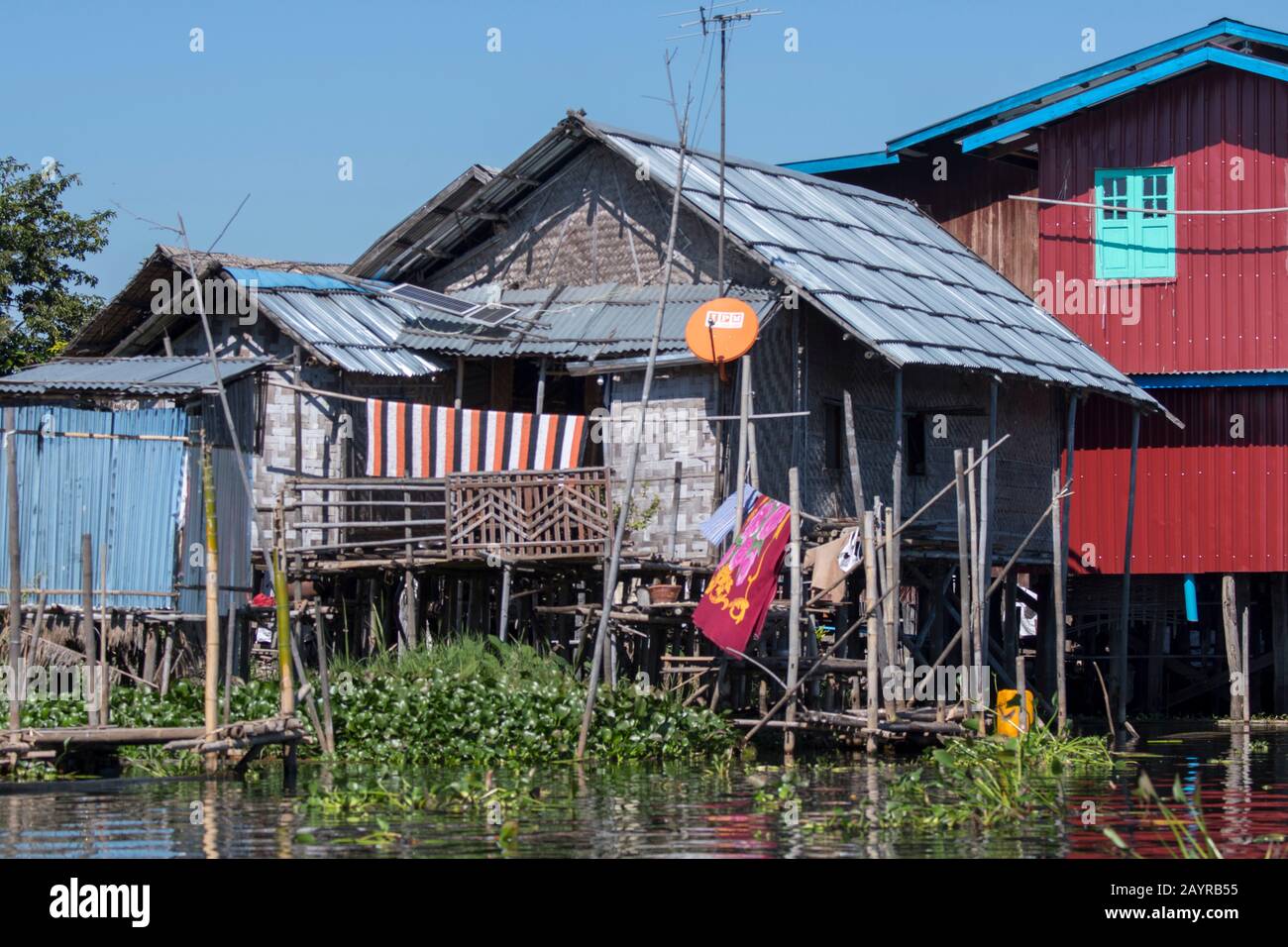A village scene with a house on stilts and a satellite dish in a ...