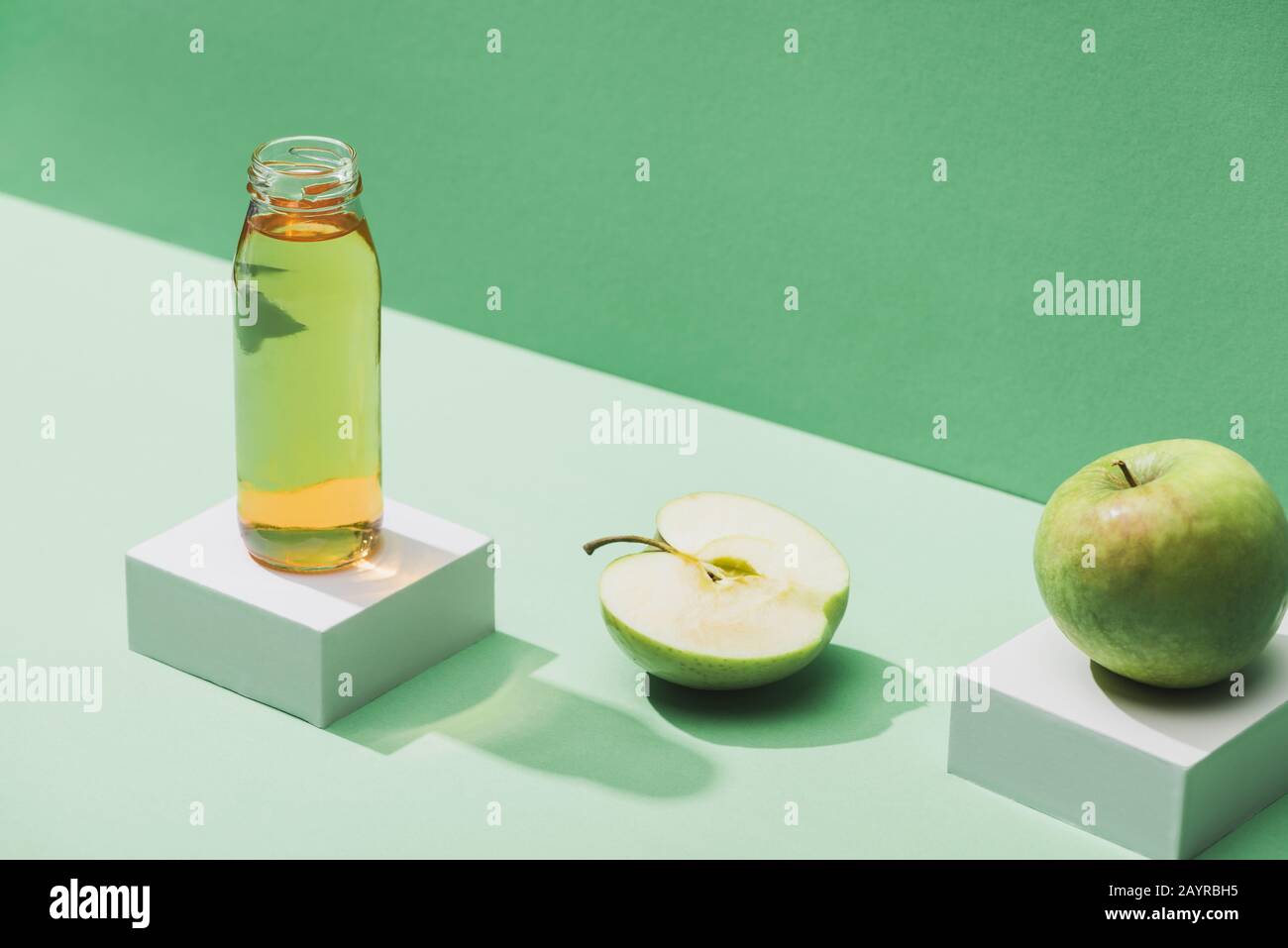 fresh juice near apples and and white cubes on green and turquoise ...