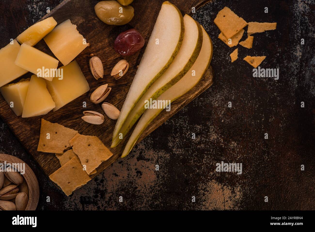 top view of cheese platter with pistachios, sliced pear, olives and ...