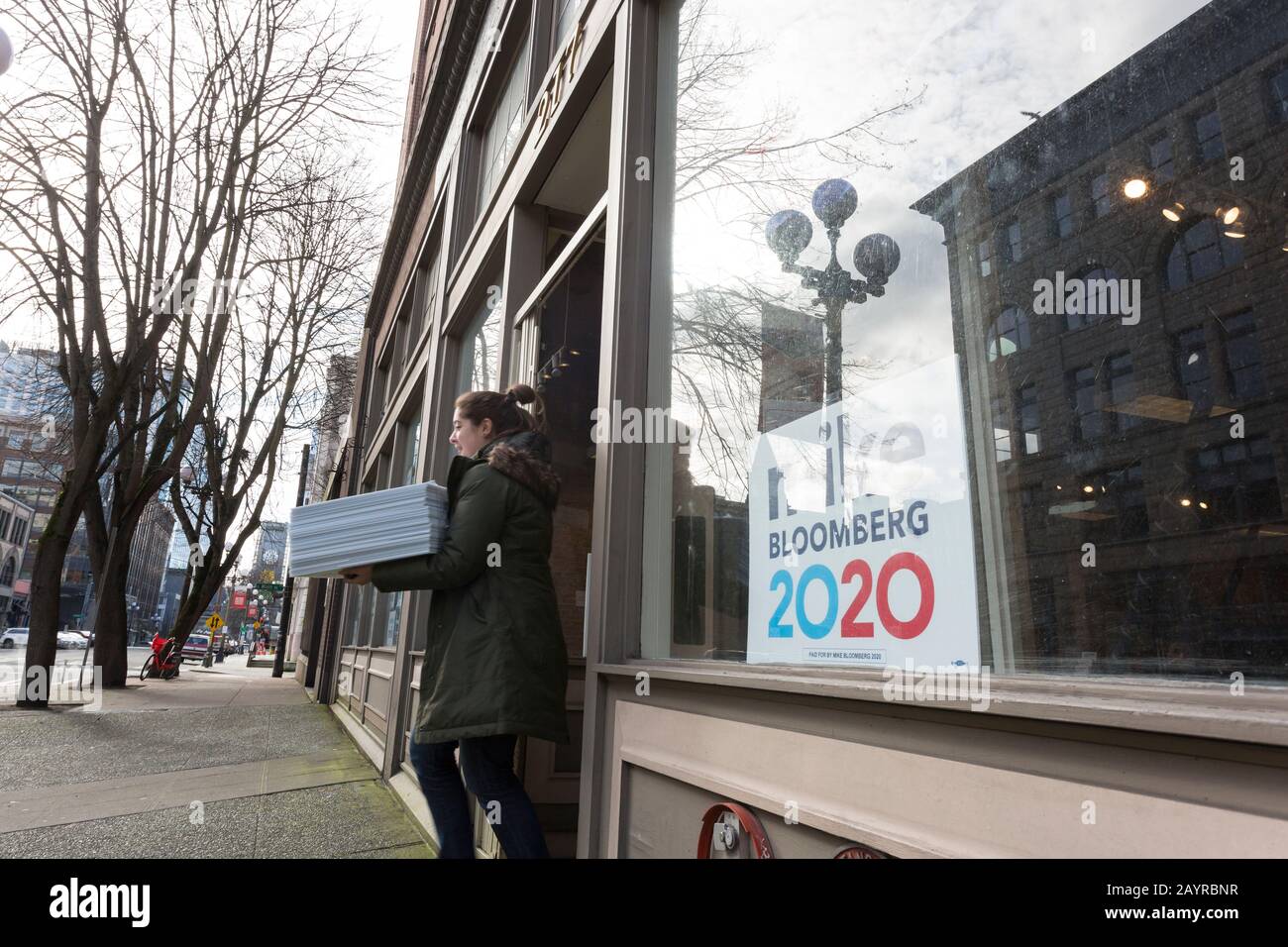 A volunteer leaves Mike Bloomberg's Seattle headquarters with a stack ...