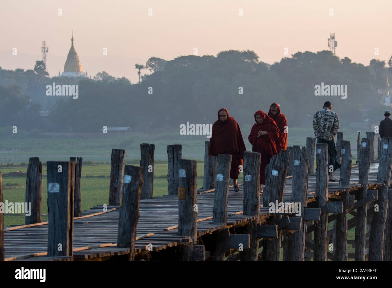 Buddhist monks are walking on U Bein Bridge (built around 1850 and is ...