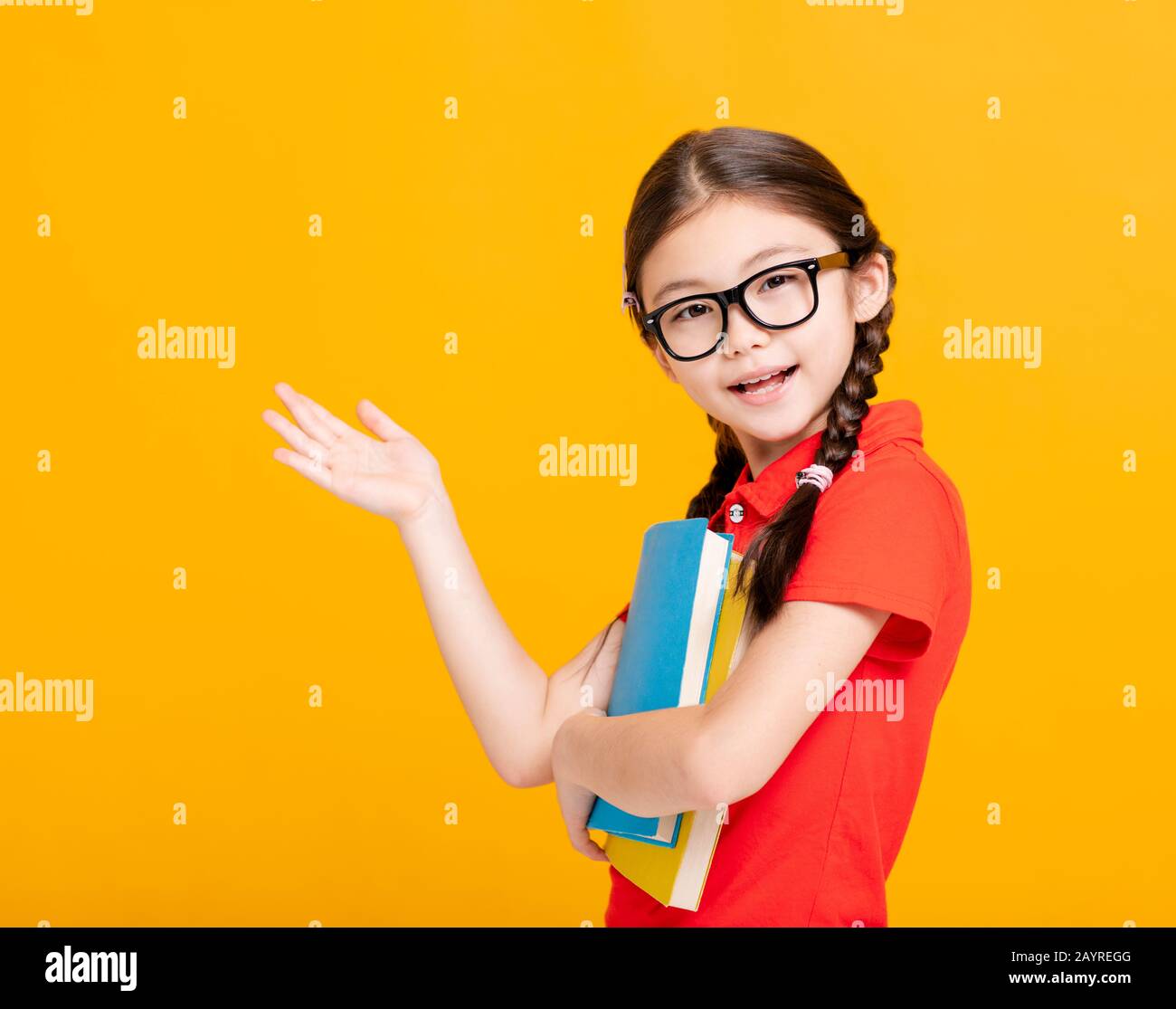 Adorable student girl holding the books and showing something Stock ...