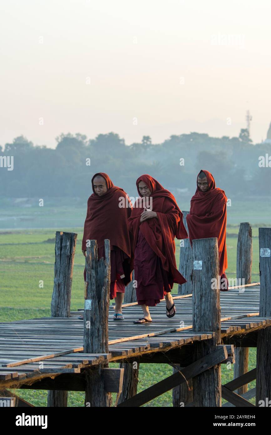 Buddhist monks are walking on U Bein Bridge (built around 1850 and is ...