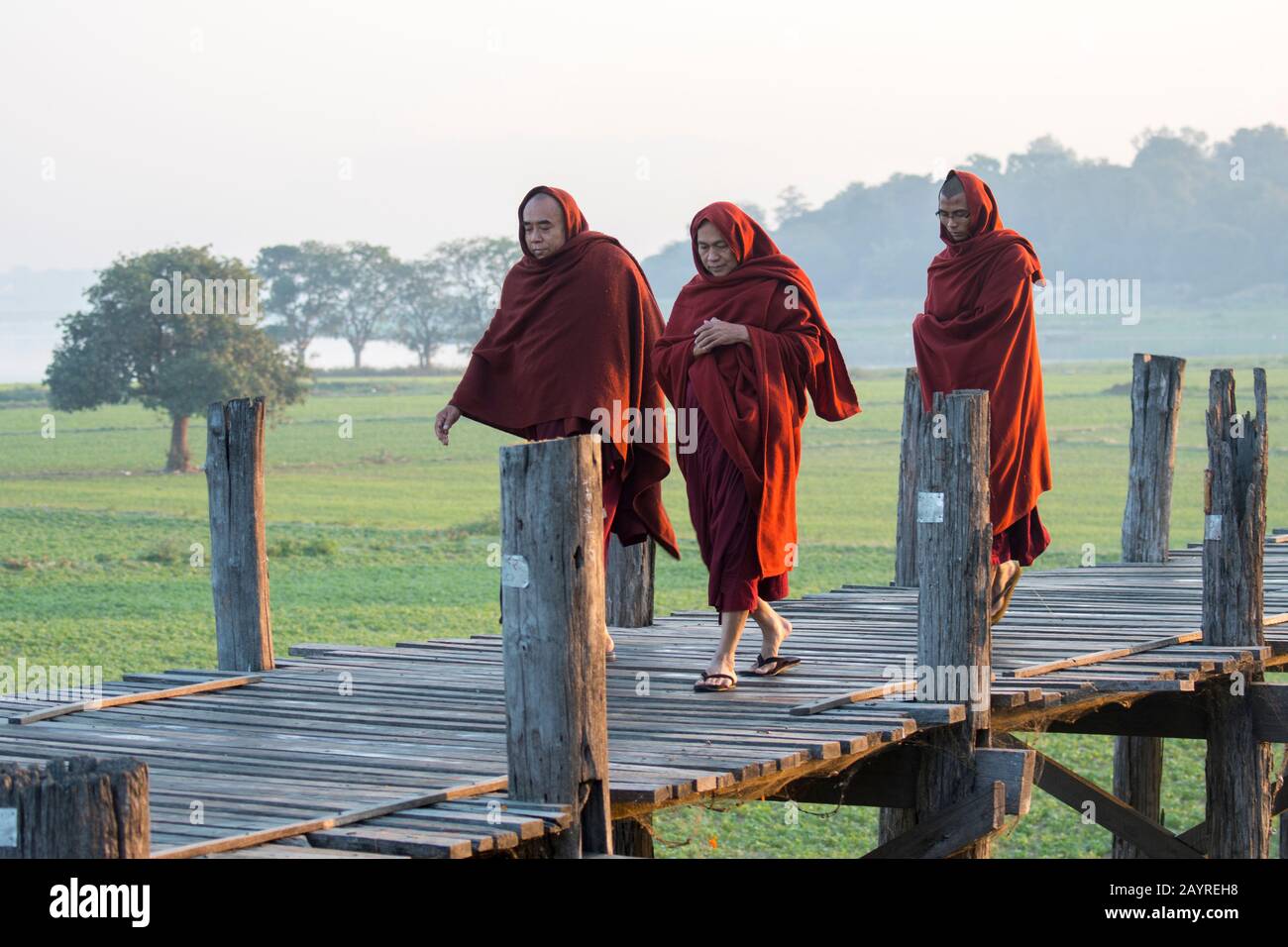 Buddhist monks are walking on U Bein Bridge (built around 1850 and is ...