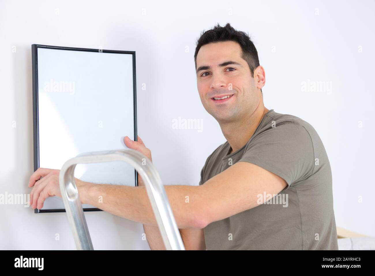 man posing putting blank frame on wall Stock Photo - Alamy