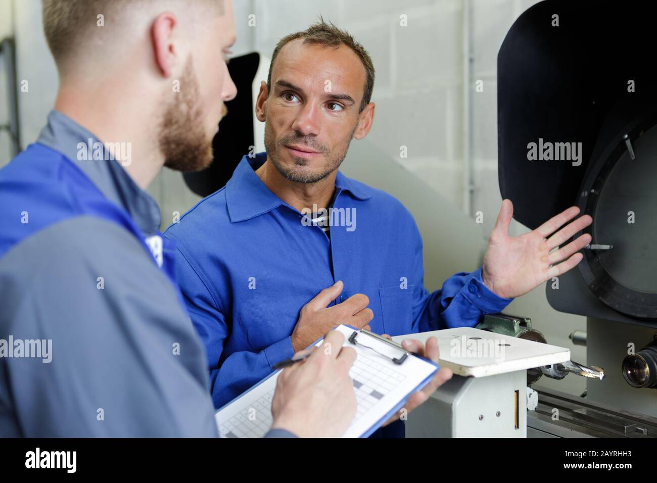 two workers wearing protective uniform talking in factory Stock Photo ...