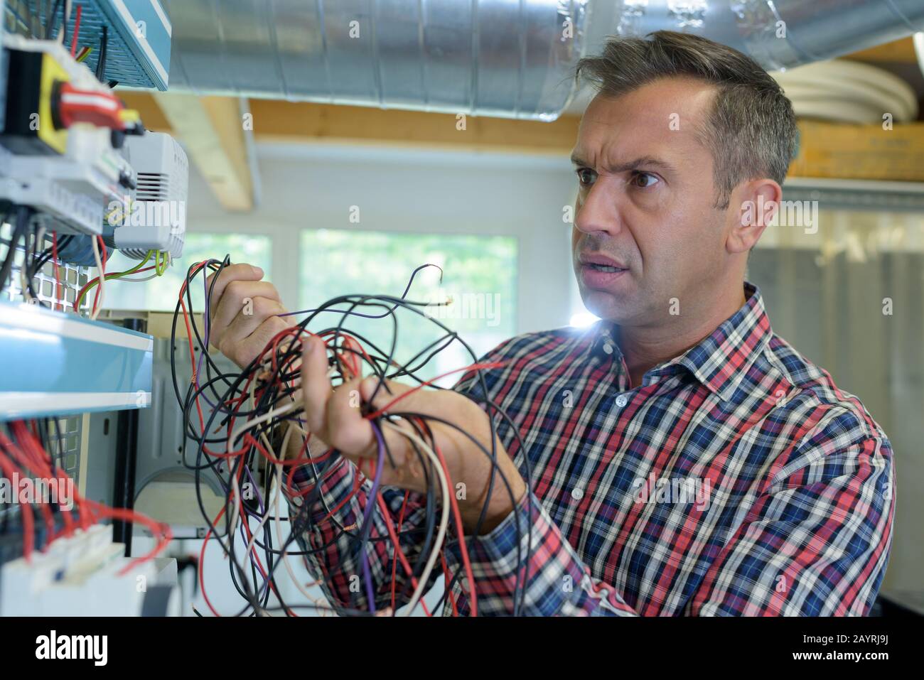 worker shocked to find electrical mess Stock Photo - Alamy