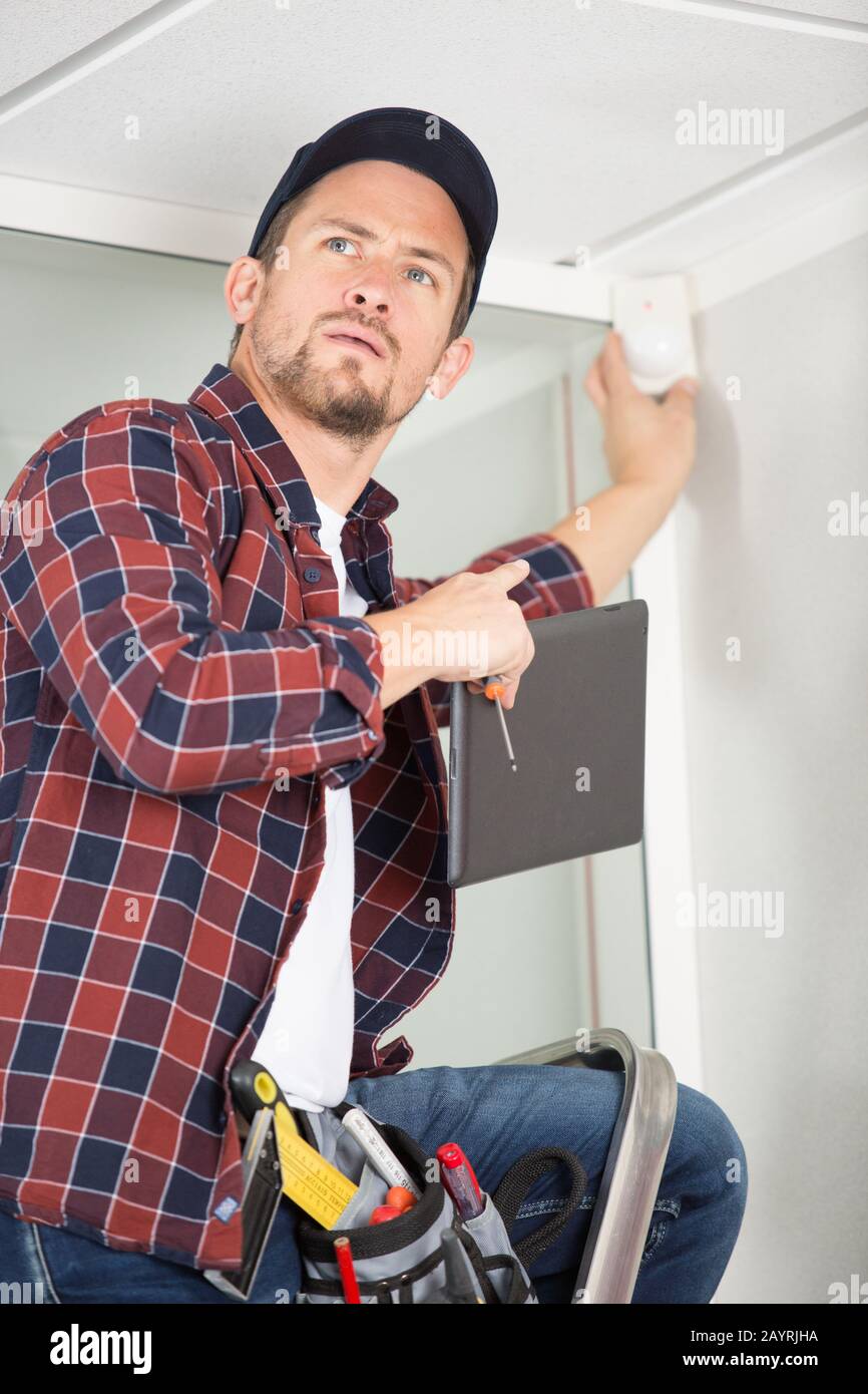 electrician installing security system sensor Stock Photo - Alamy