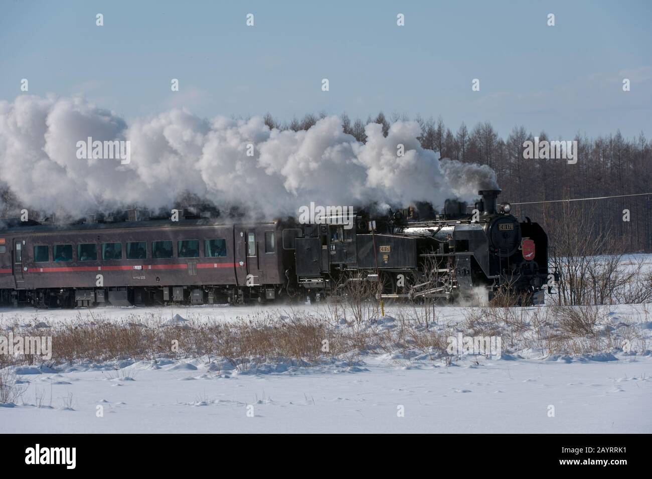 A steam train is going through the countryside in the winter near the ...