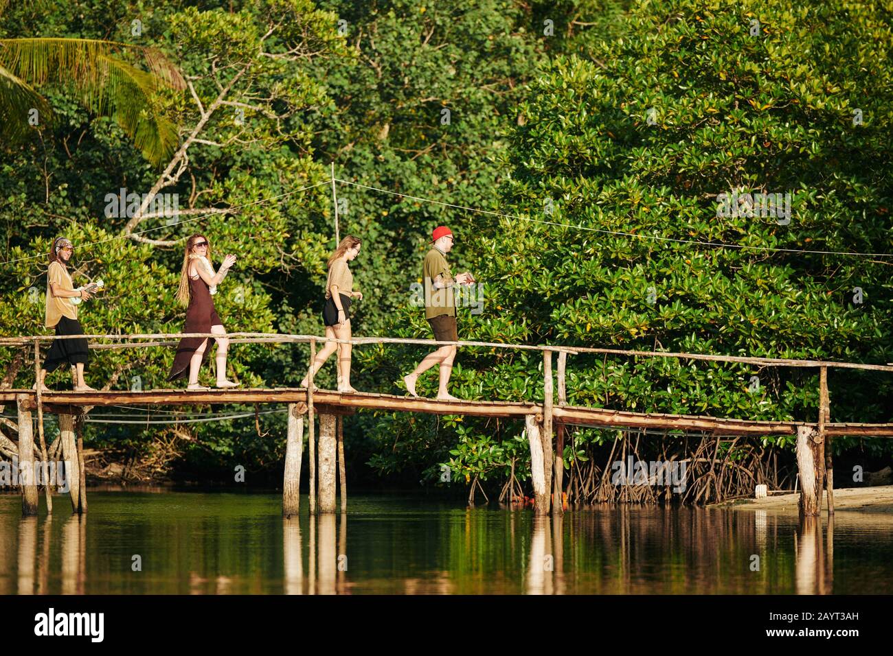 Happy excited young people walking on wooden bridge over small river ...