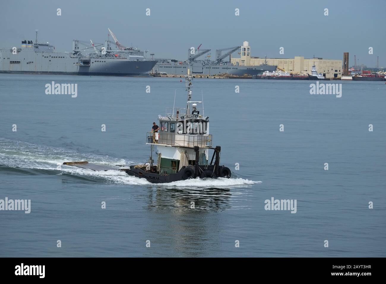 A small utility 'tug' boat working on Upper Bay with navel ships in the ...