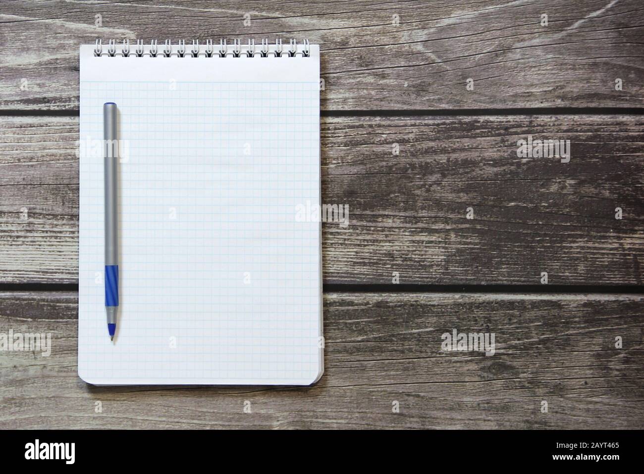 Notepad with a blank white sheet in a checker paper with ball pen lies ...