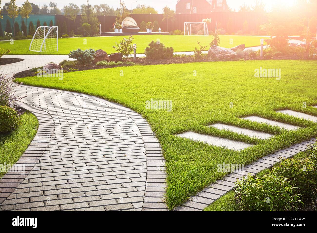 Landscaping of the garden. A tile path between green grass and a lawn ...