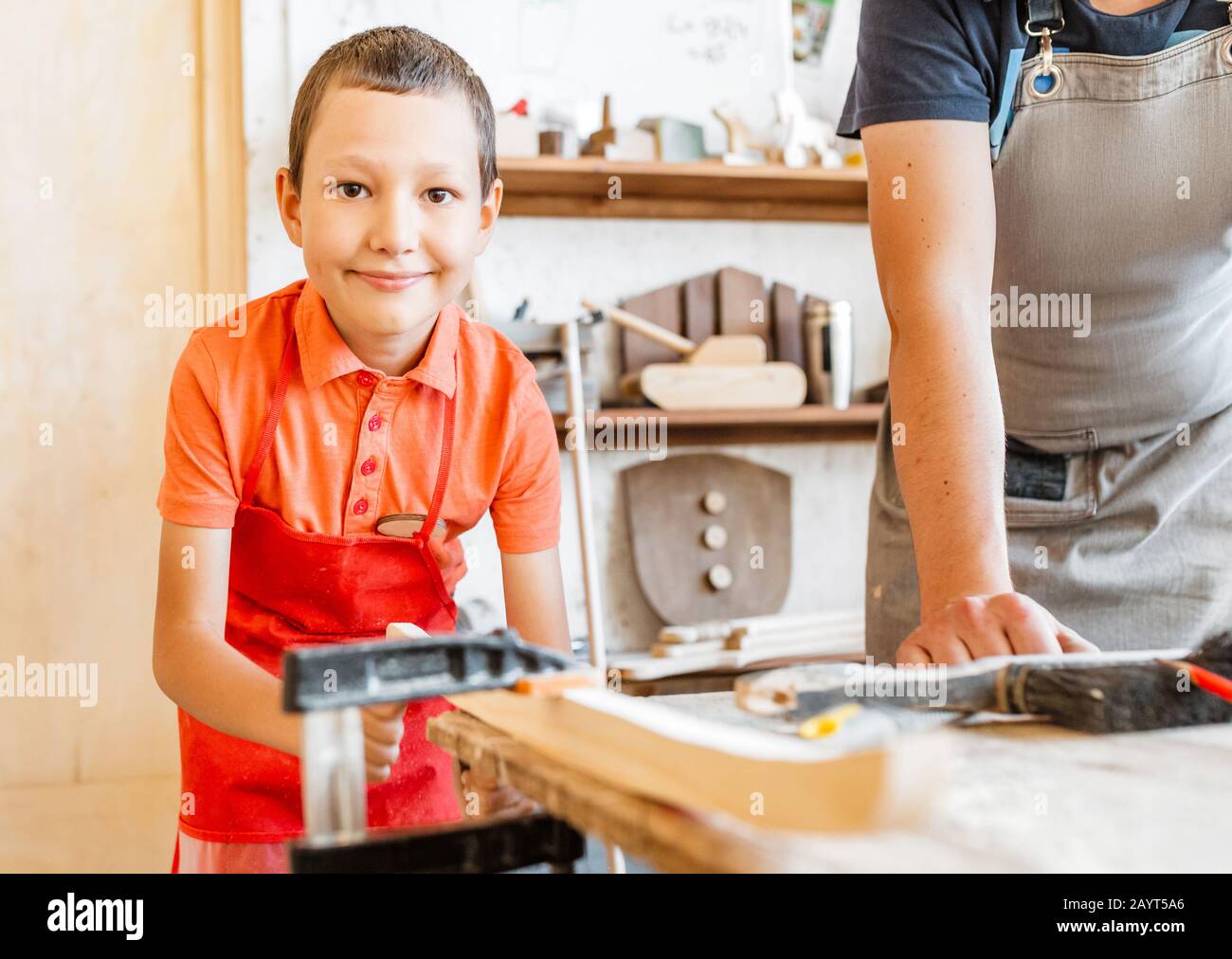father and little son working together with wood plank at workshop ...