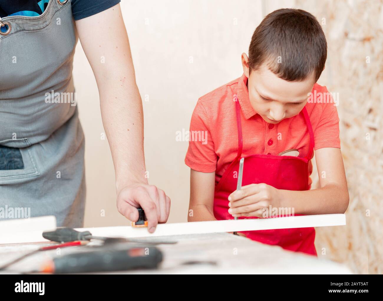 father and little son working together with wood plank at workshop ...