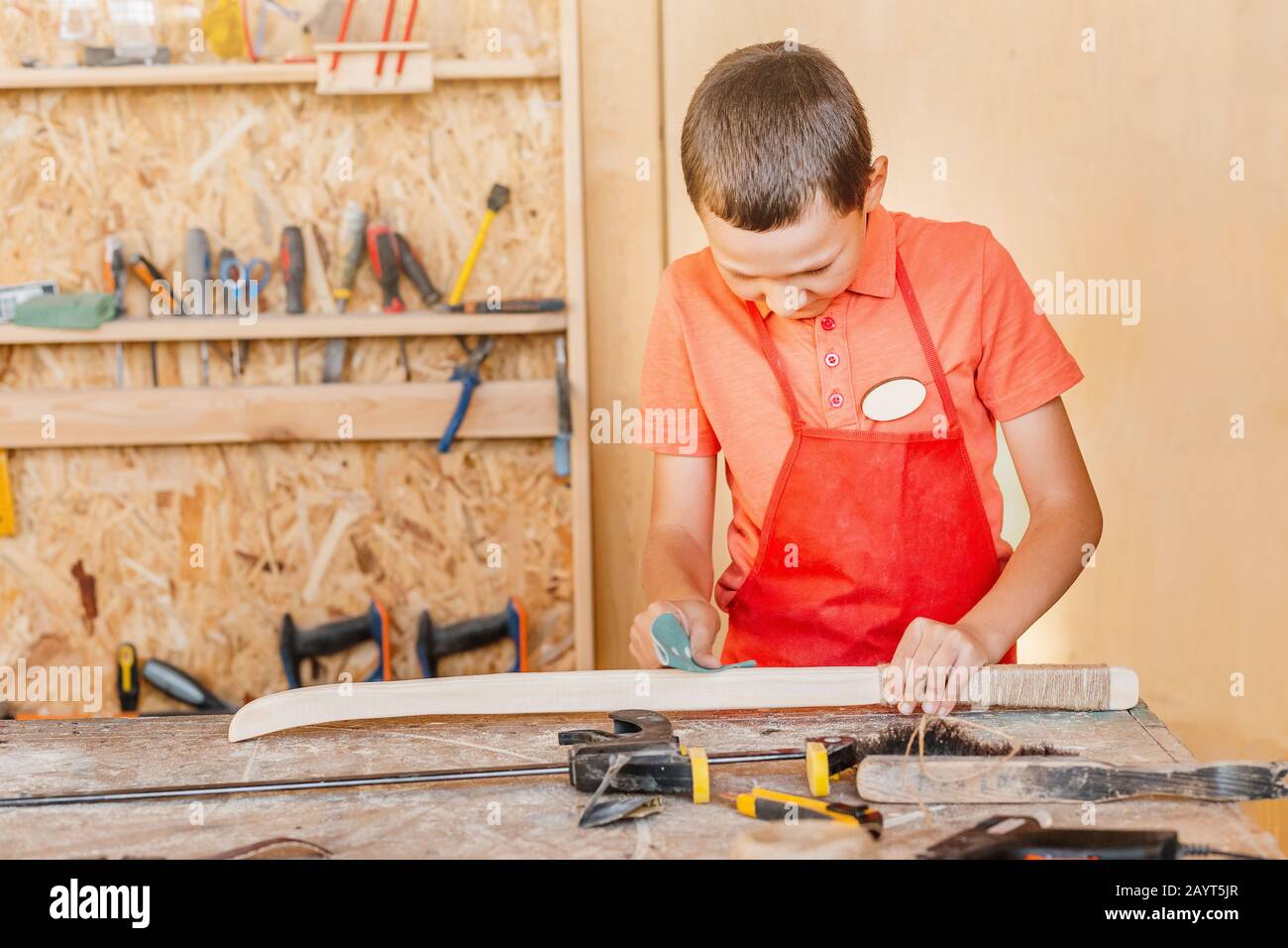 Little talented genius boy works with wood in a carpentry workshop. The ...