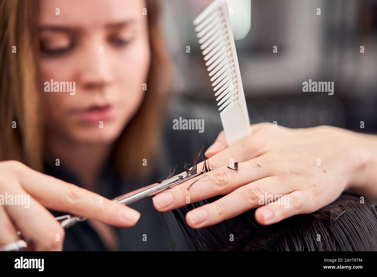 Beautiful caucasian woman hairdresser doing hairstyle to client. Close ...