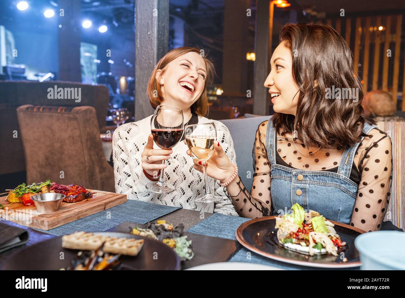 Two girls friends chatting and drinking wine in a restaurant in a ...