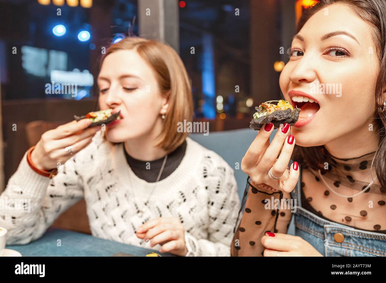 Two girlfriend girls chat and laugh in the restaurant and eat Spanish ...