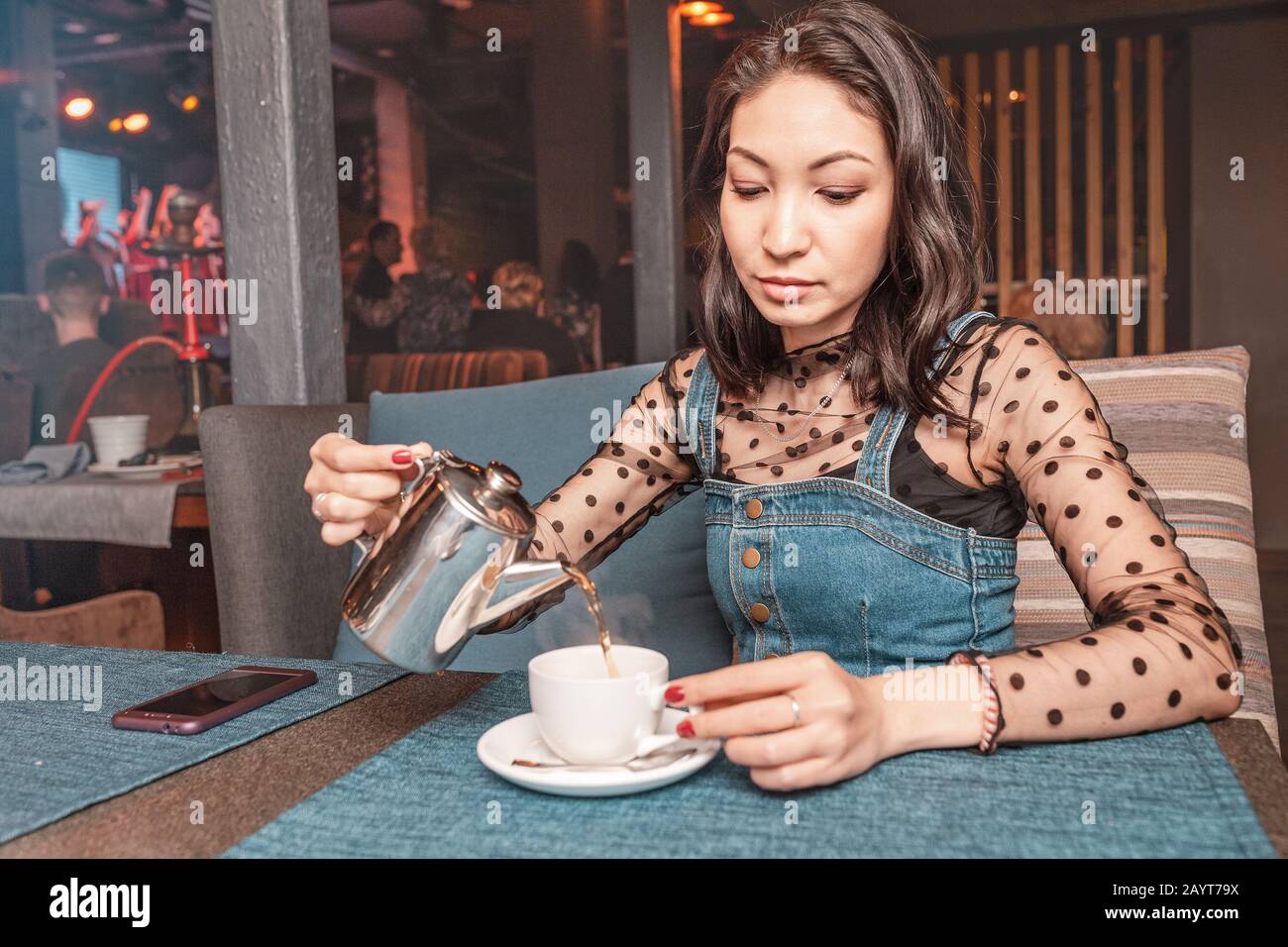 A woman pours tea from a kettle in a restaurant Stock Photo - Alamy