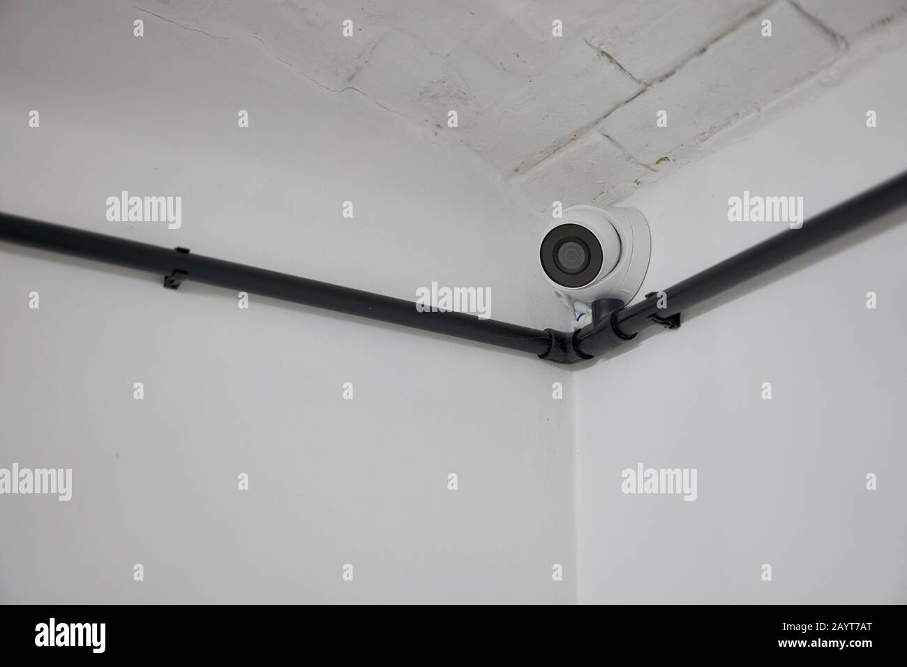 White round cctv camera installed in the corner on a white wall ...
