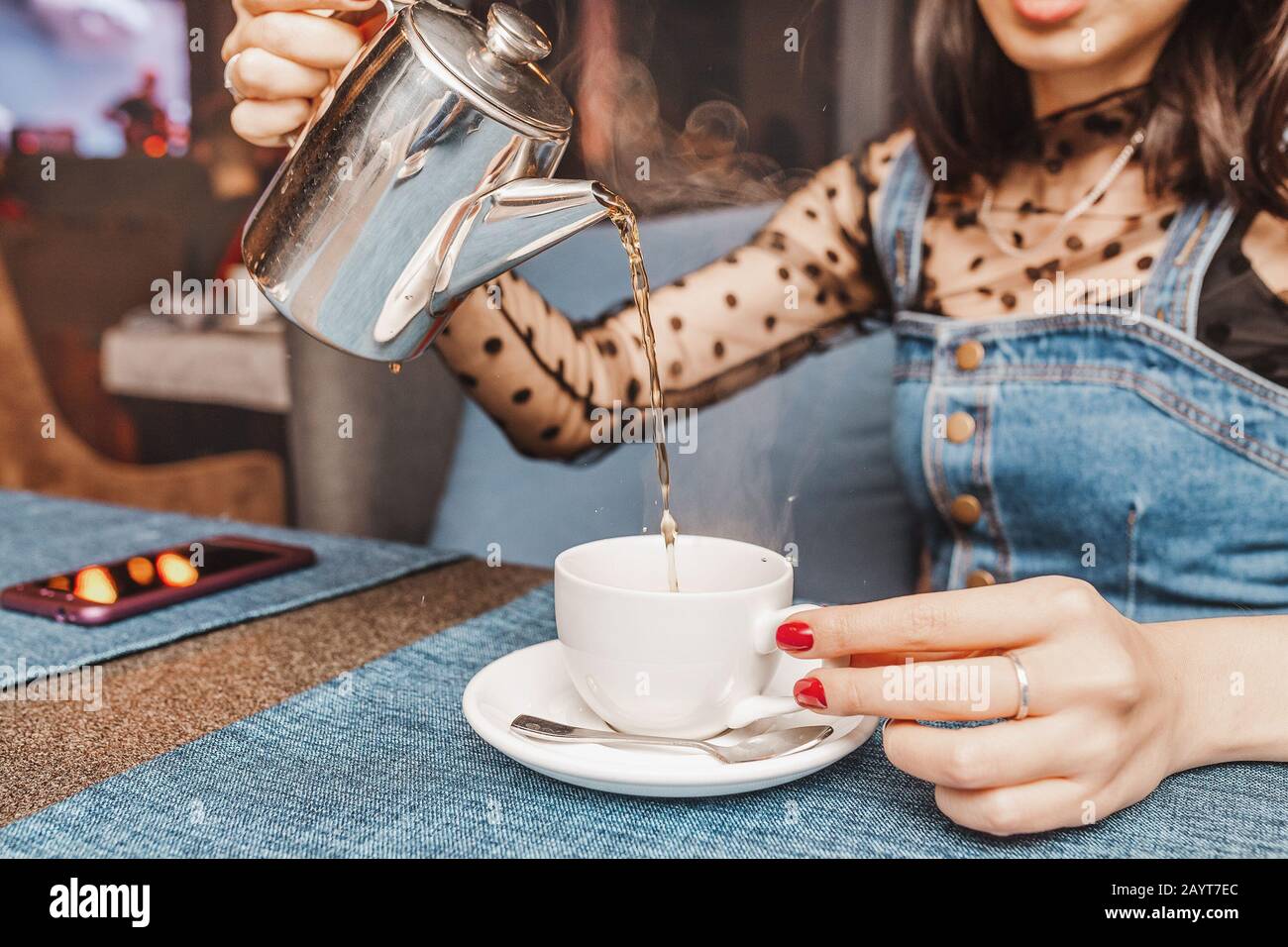 A woman pours tea from a kettle in a restaurant Stock Photo - Alamy
