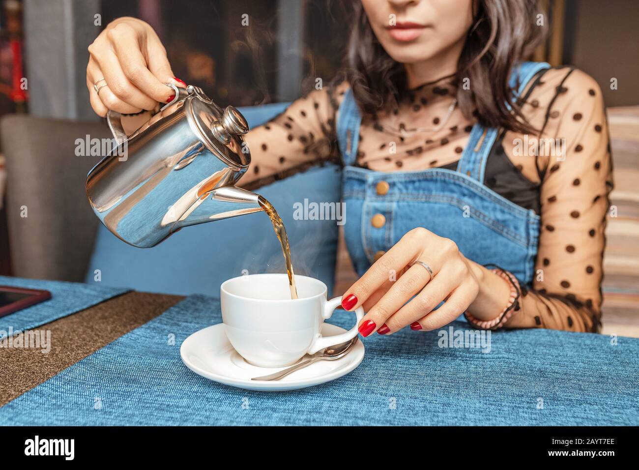 A woman pours tea from a kettle in a restaurant Stock Photo - Alamy