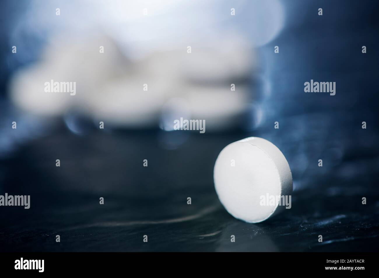 Close-up of an upright round tablet on a slate backlit with lens flares ...