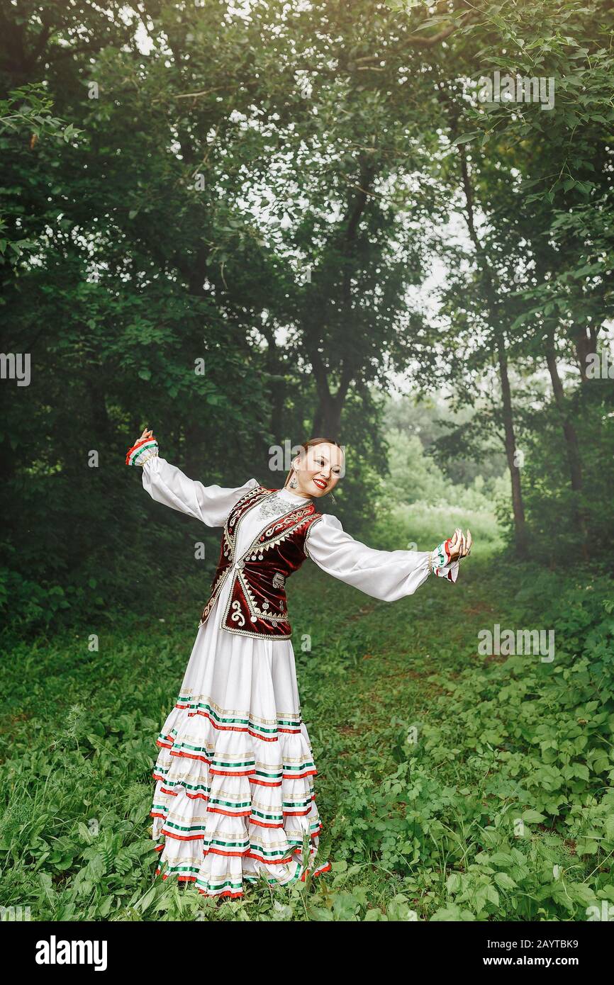 A woman in traditional embroidered Turkic Eastern clothes performs a ...