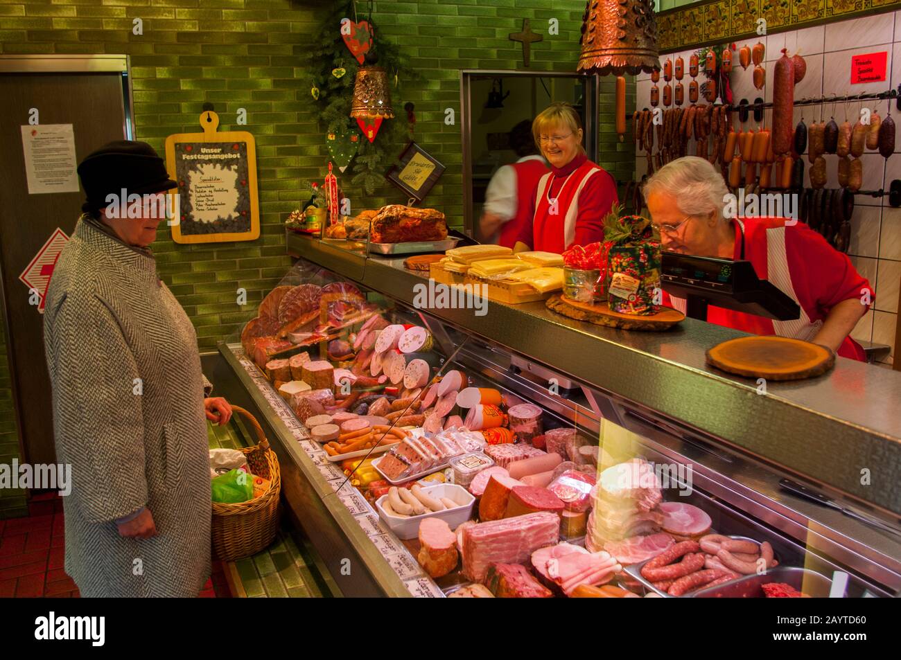 Woman buying meats and sausages in a butcher store at the market square ...