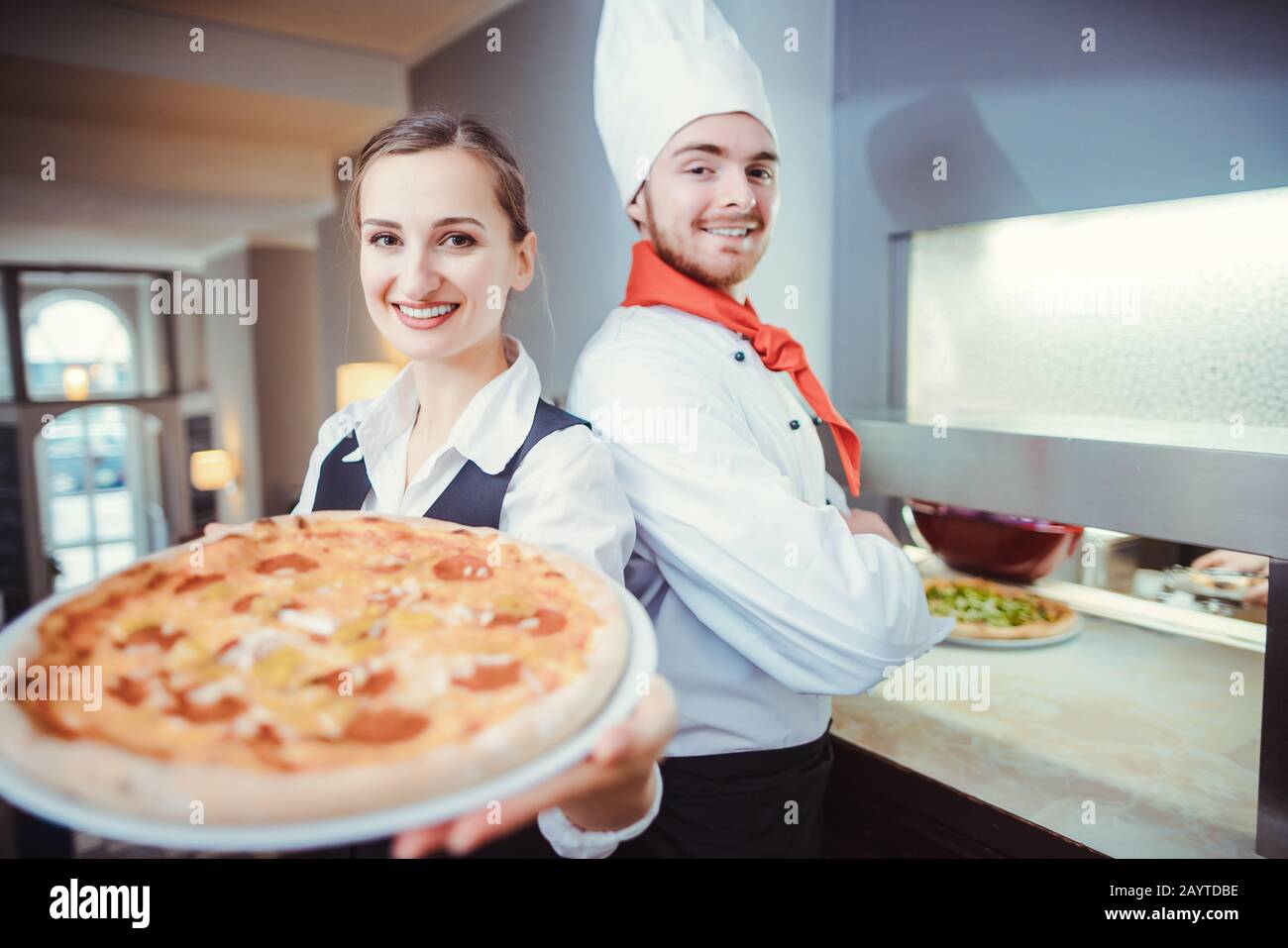 Chef cook and waitress presenting a pizza in restaurant Stock Photo - Alamy
