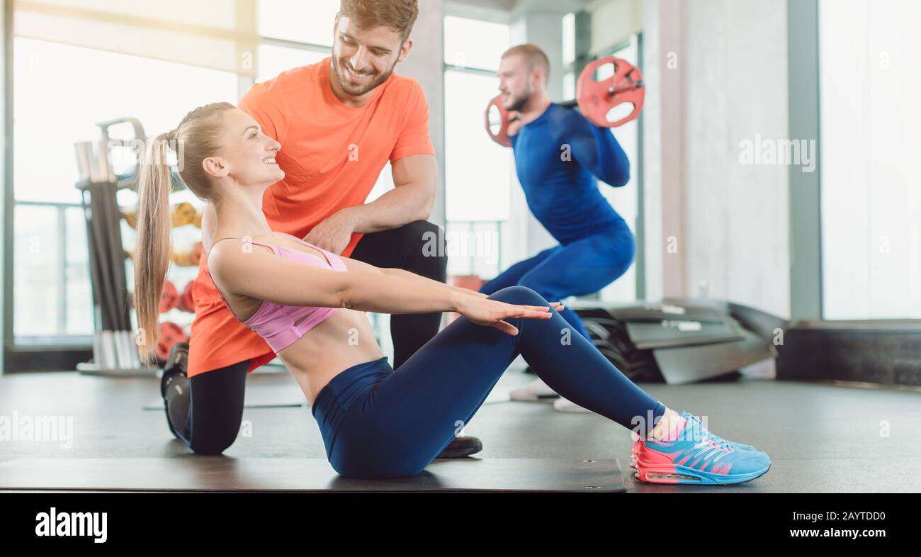 Personal coach helping fit woman in the gym with her exercises Stock ...