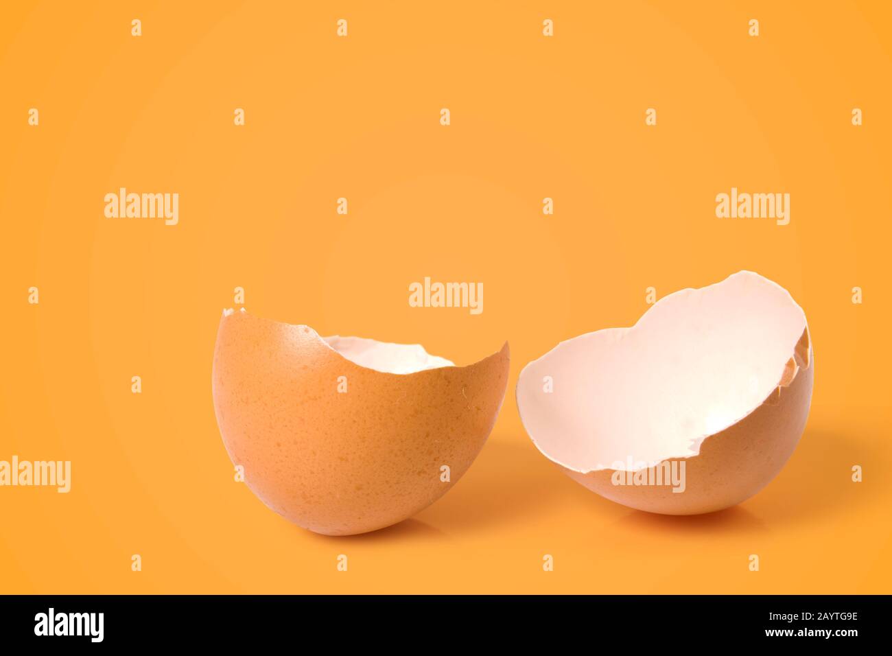 Cracked eggshell in vibrant color on orange background Stock Photo - Alamy