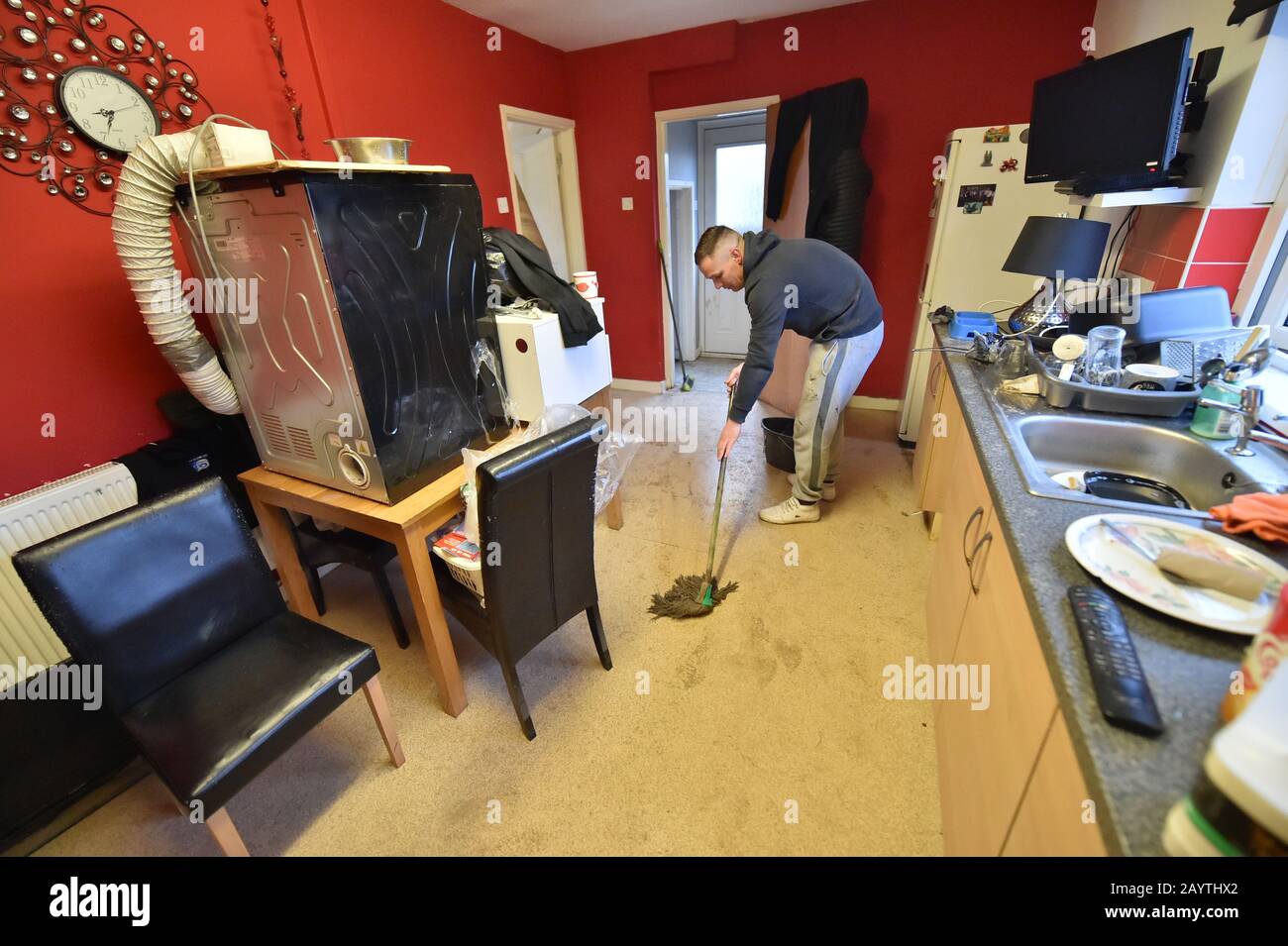 Lee Griffiths mopping the kitchen floor after flooding damaged his ...