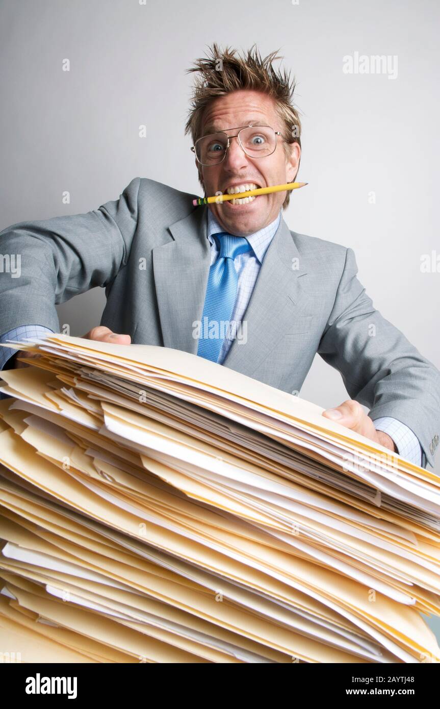 Stressed businessman with pencil in his mouth trying to lift a massive ...