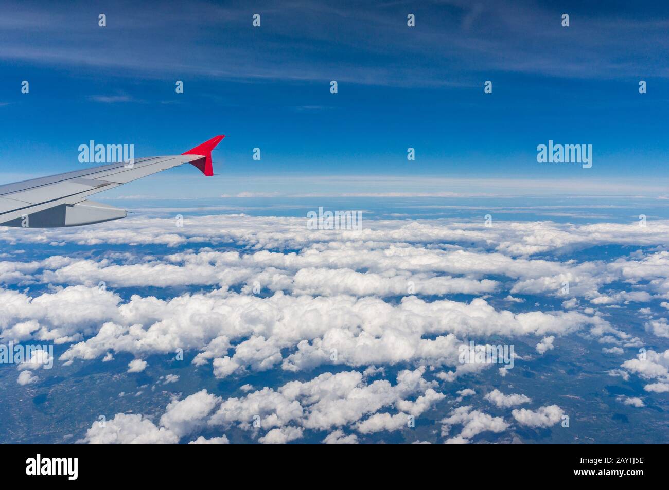 Aircraft wing with red tip and clouds landscape. Air travel concept ...