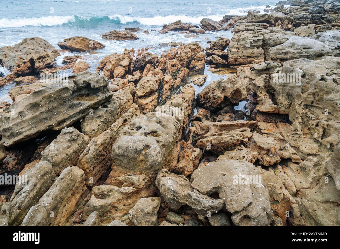 Close up of rock erosion surface on ocean coast with waves on the ...