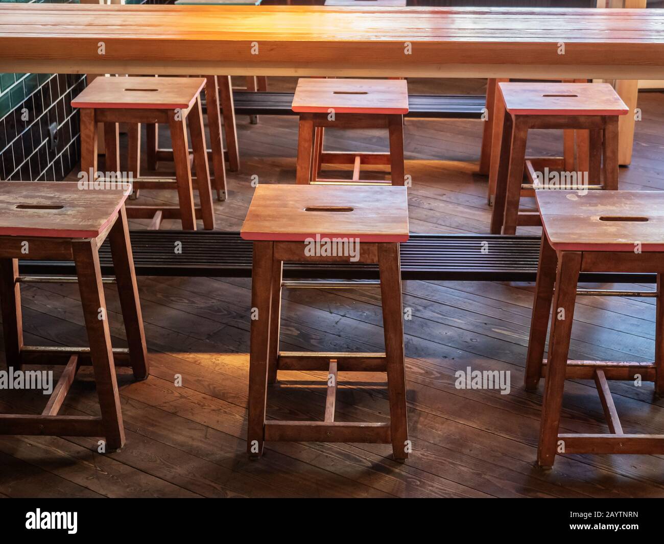 Wooden stools standing on wooden floor on either side of the table ...