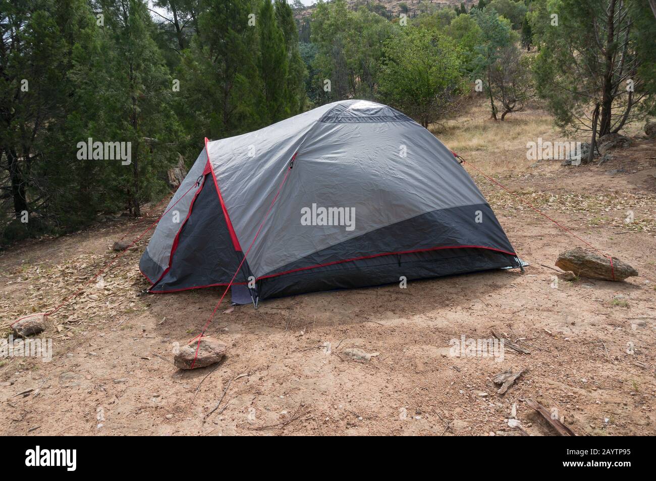 Dome shaped camping tent set on dry ground with rocks. Outside summer ...