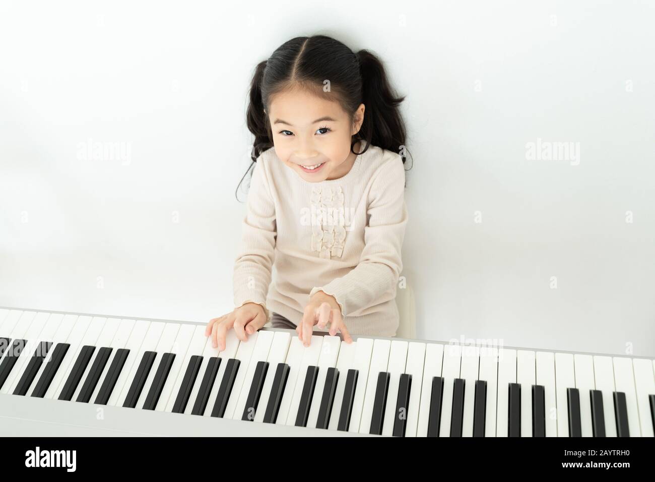From above of positive smiling adorable Asian girl practicing music ...