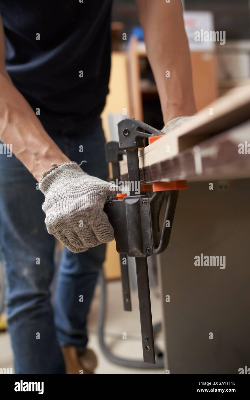Man joiner in gloves clamps board in vice at workshop , close-up Stock ...